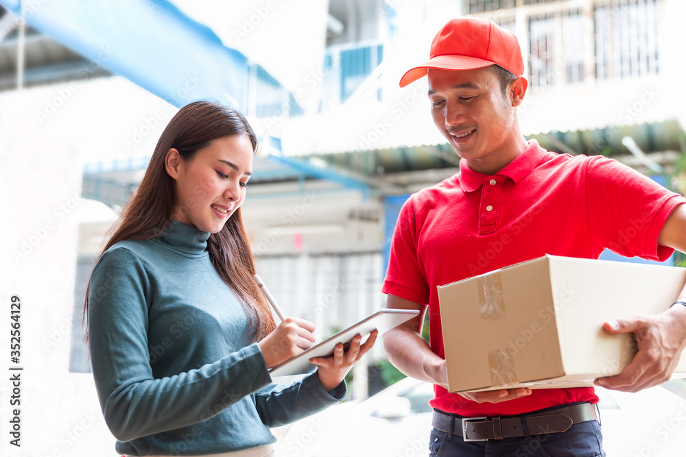Woman signing forms on the digital tablet and receiving parcel from ...
