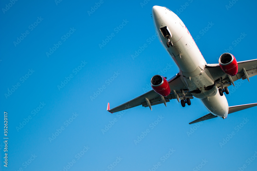 View from below of white jet aircraft on blue clear sky background with ...