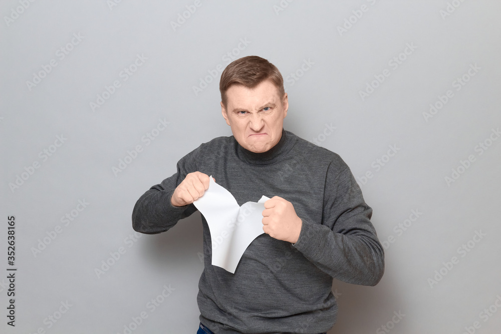 Portrait of angry furious blond mature man tearing paper sheet Stock ...