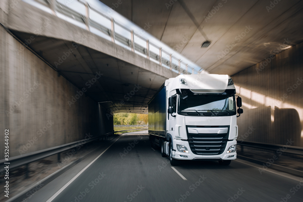Semi-truck with cargo trailer driving at the tunnel. Fast moving truck ...