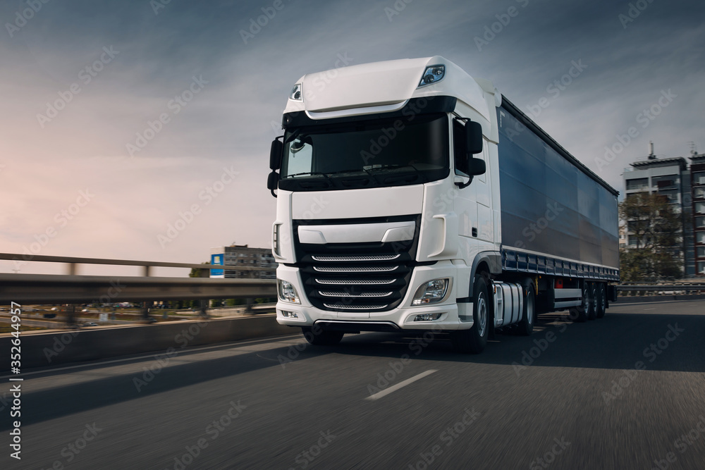 Semi-truck with cargo trailer driving at the city streets. Fast moving ...