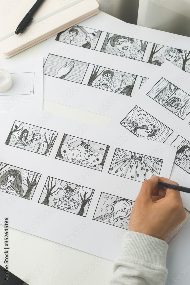 The hands of an illustrator painter draw a storyboard for a movie or ...