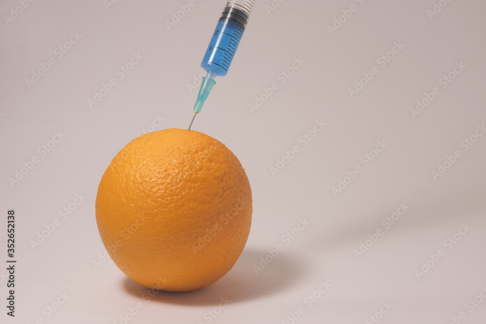 Foto de Injecting blue liquid into an orange fruit. Syringes for ...