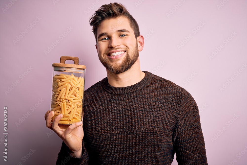 Young blond man with beard and blue eyes holding bottle of Italian dry ...