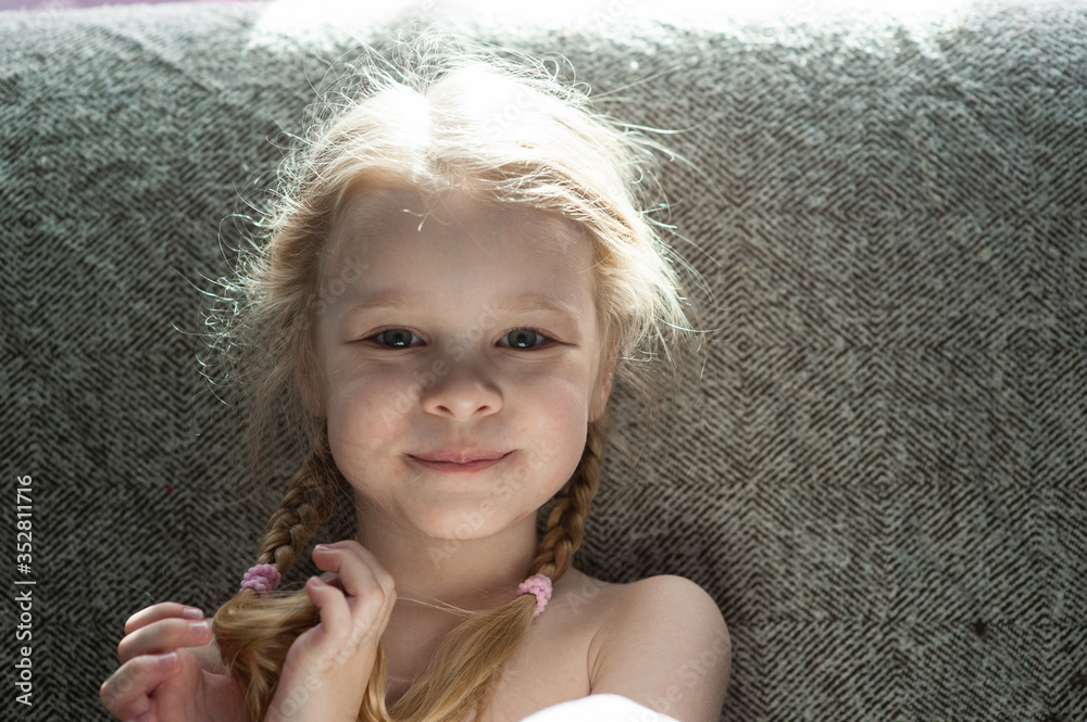 Little blond girl with pigtails smiling. Little girl holds her pigtails ...