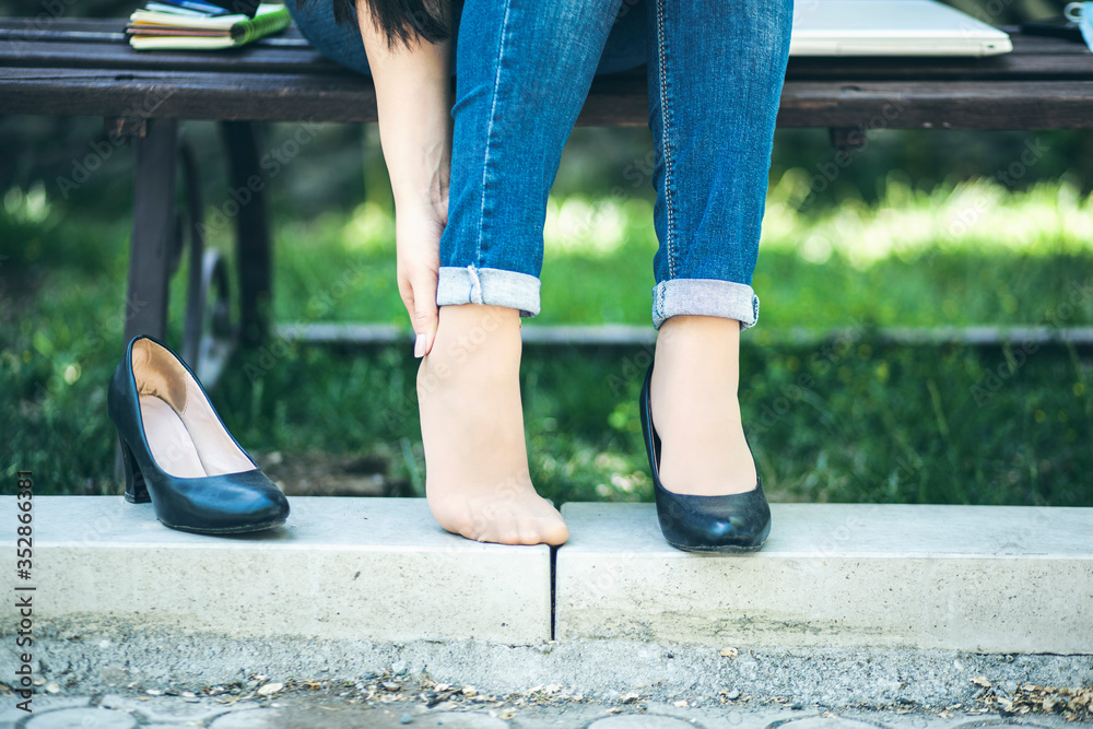 The girl, tired of heels, takes off her shoes from her feet and sits ...