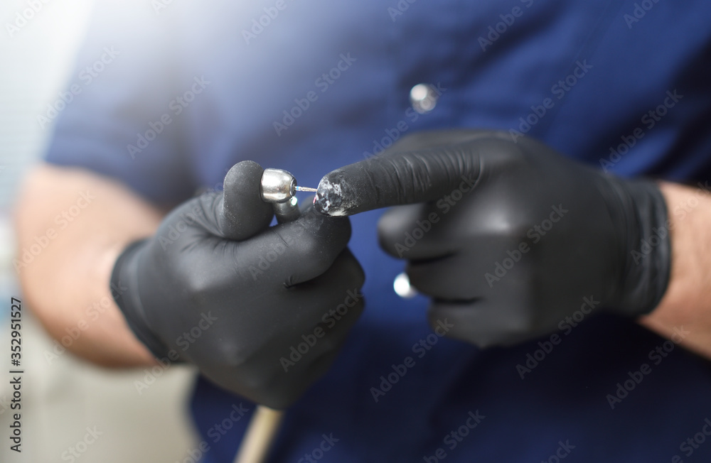 The dentist prepares a drill for treating a tooth and installing a ...