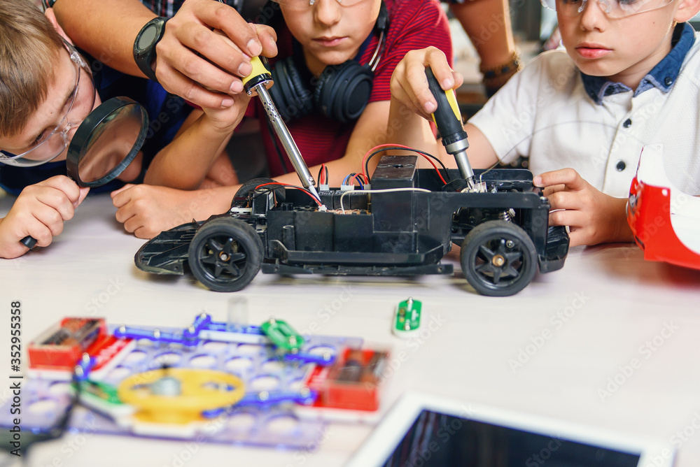 Foto de Male electronic engineer with european school children working ...