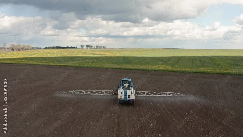 Aerial image of tractor spraying soil and young crop in springtime in ...