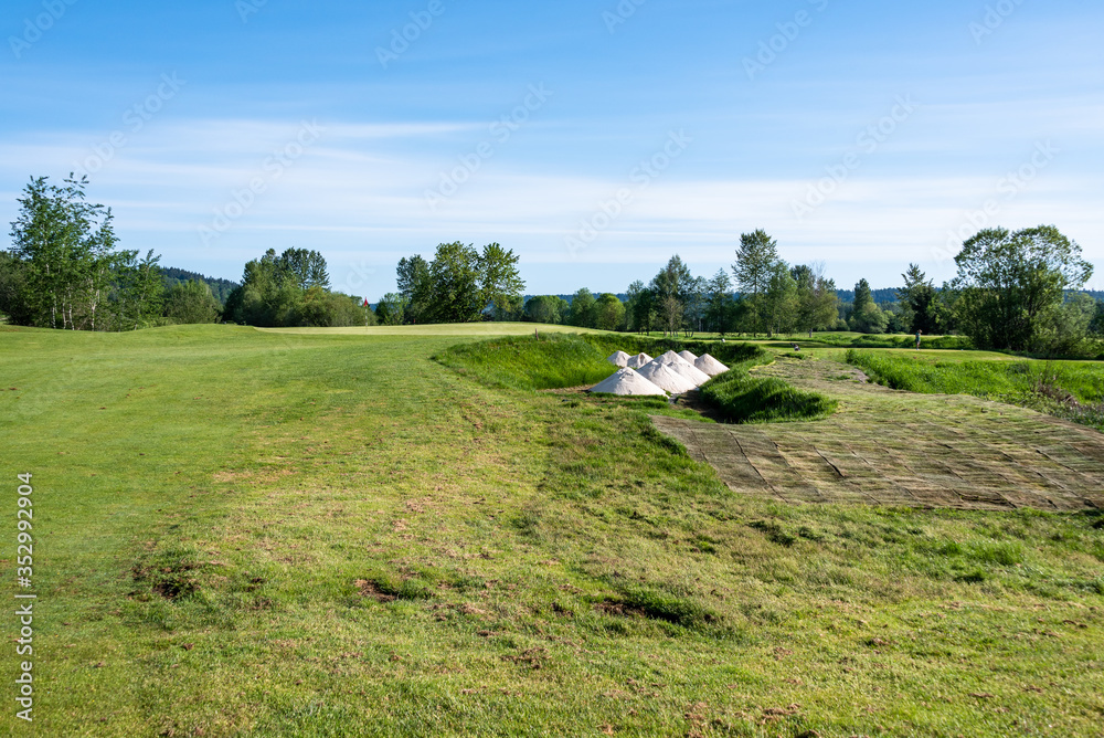 Early morning on the golf course, sand bunker under maintenance with ...