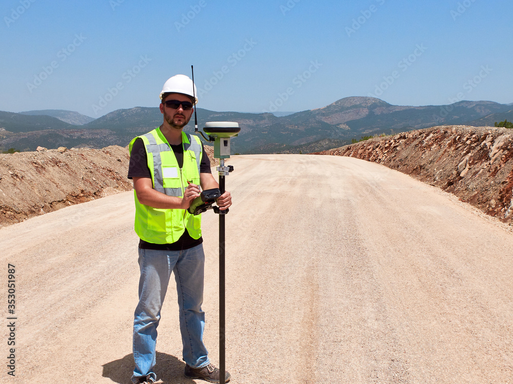 Geodetic engineer surveyor in white hard hat doing measurements with ...