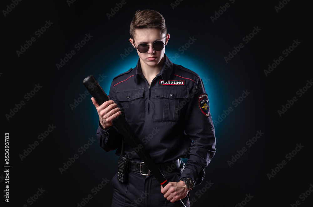 handsome guy in a police officer's uniform with a baseball bat. english ...