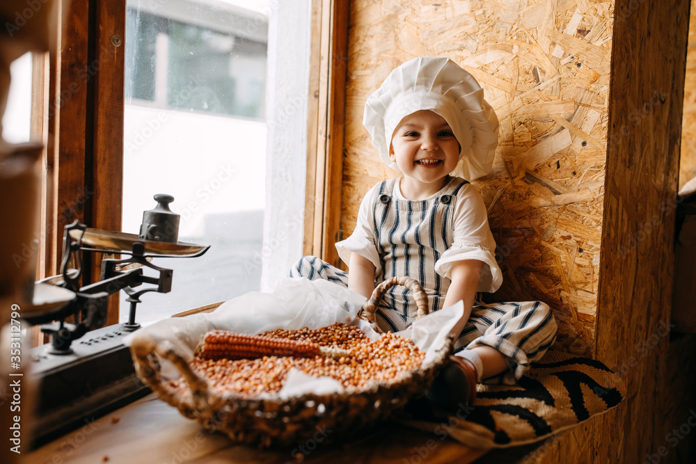 Little child playing with dry corn grains in a basket, sitting on a ...