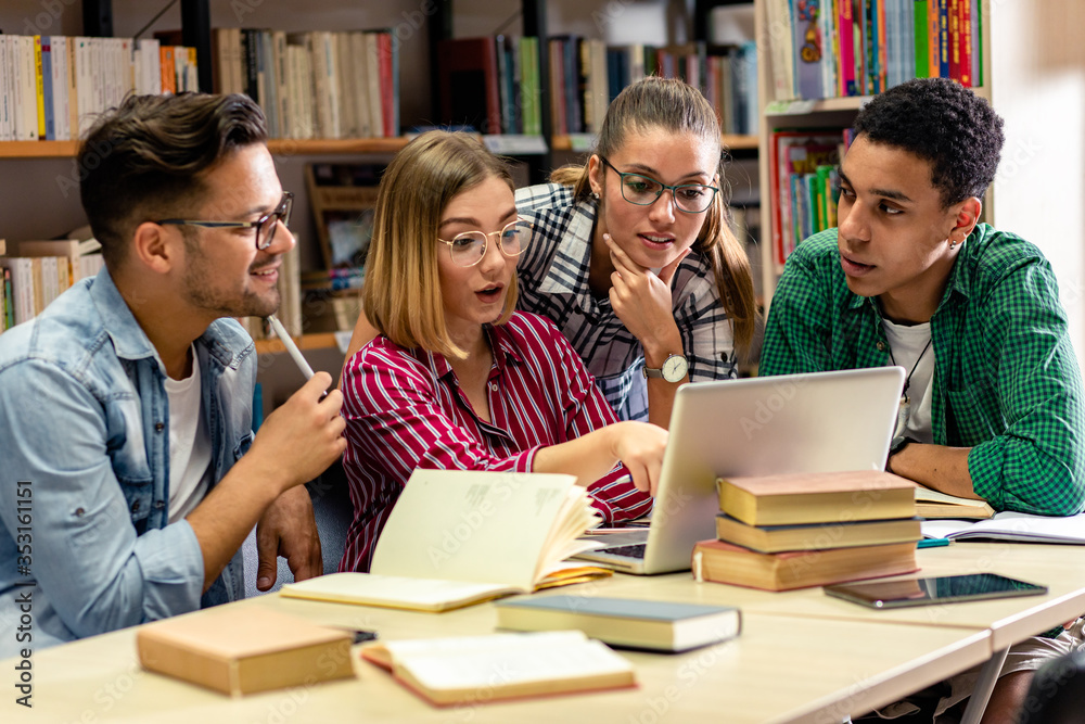 Four young students study in the school library, they using laptop for ...