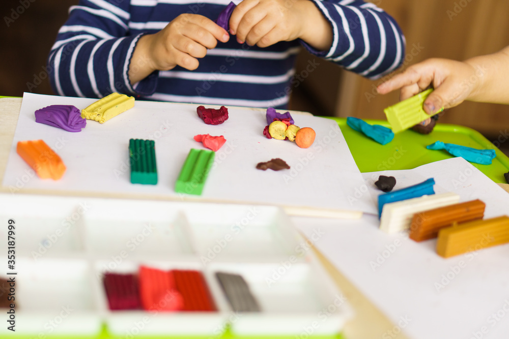 Little girl playing with plasticine on a table in the nursery sitting ...