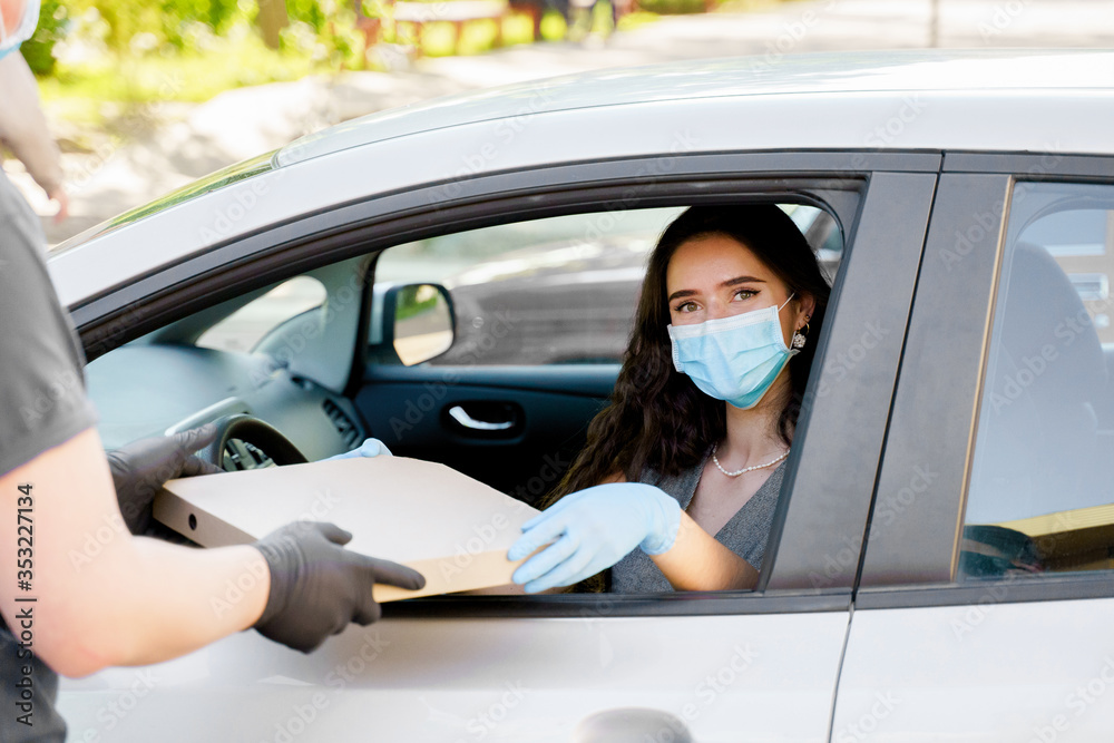Food delivery courier gives pizza to woman in eco car. Safety food ...