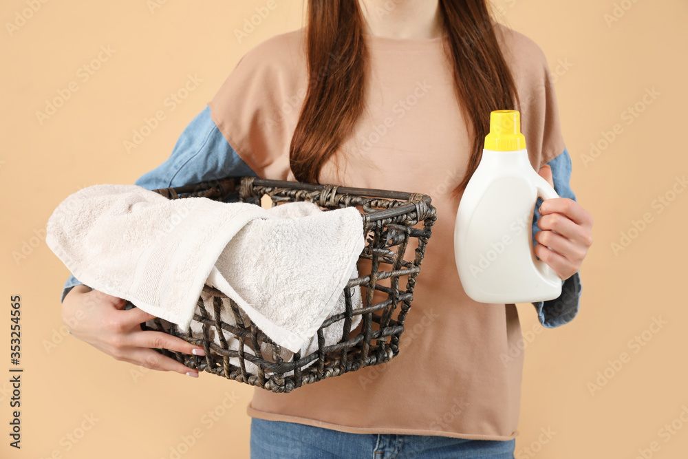 Beautiful young woman with laundry and detergent on color background ...