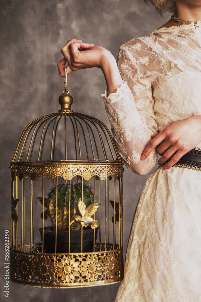 Foto de woman in a white lace dress holding a golden cage with gold ...