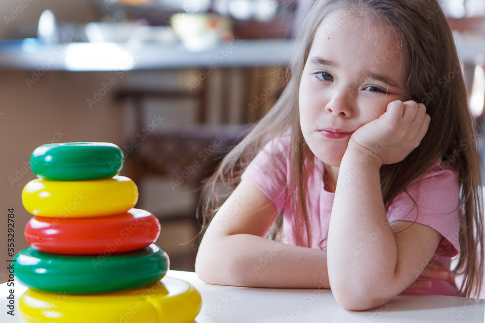 child is bored while collecting tpyramid details of toy, sad face ...
