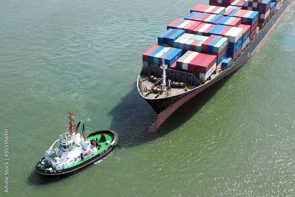 Tugboat operation, pulling a large Container Ship away from dock. Stock ...