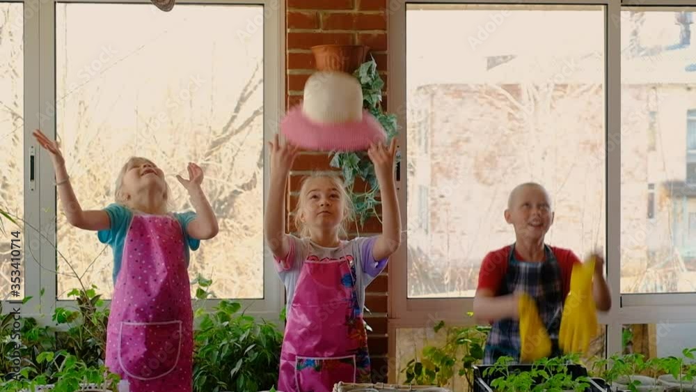 three children gardeners throw hats and gloves up on the veranda ...