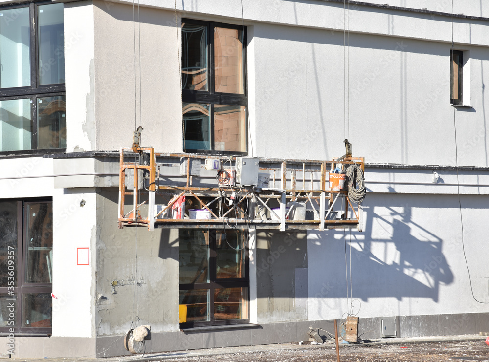 Suspended construction cradle on the background facade of the building ...