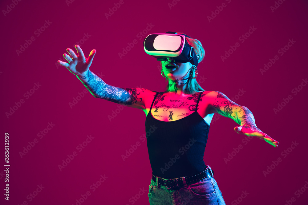 Playing with VR-headset. Young caucasian woman on purple studio ...