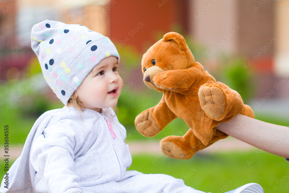 Baby child with favorite toy plays with his mother teddy bear park for ...