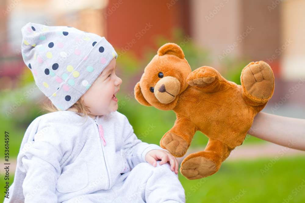 Baby child with favorite toy plays with his mother teddy bear park for ...