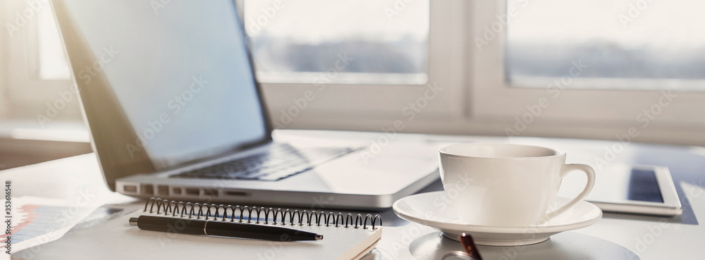 Workplace, laptop computer, coffee cup and notebook at office desk ...