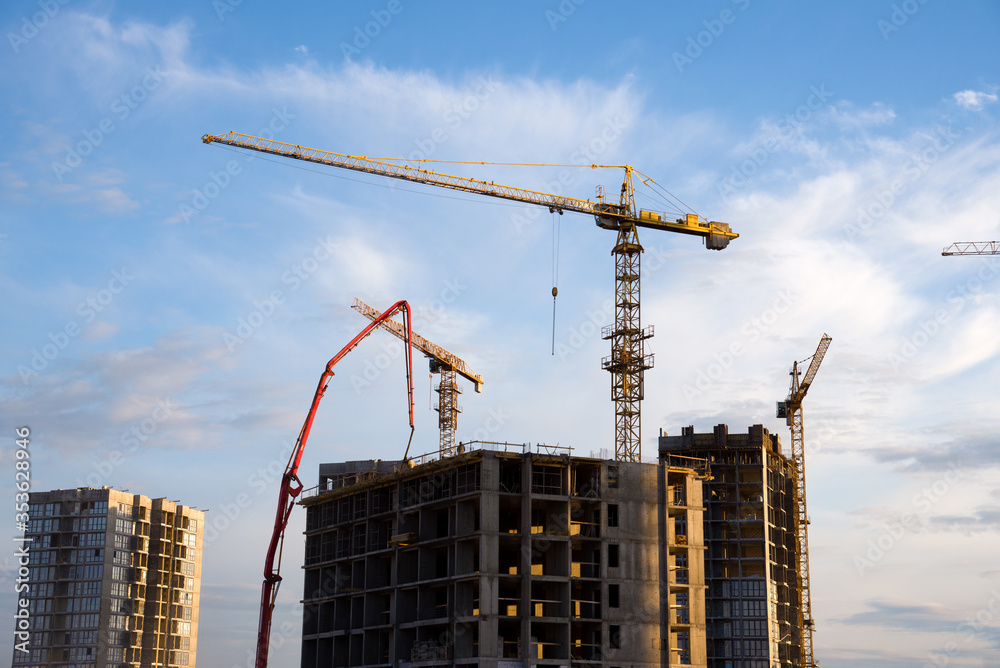 Tower crane and builders in action on blue sky background. Workers ...