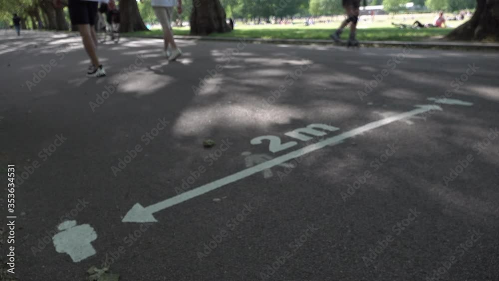 People walk and cycle past pavement markings in a park that show two ...