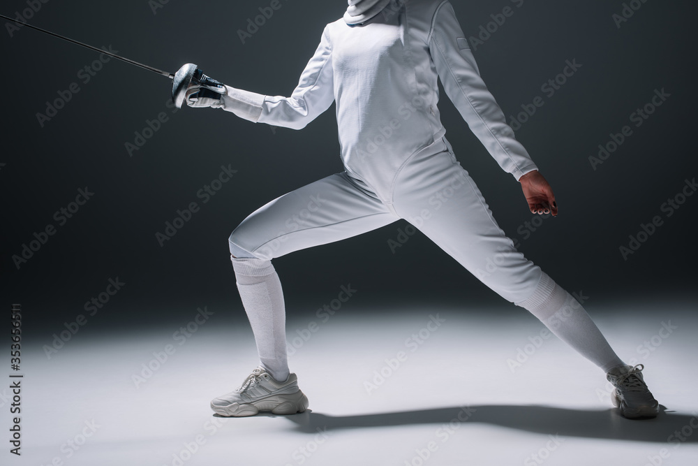 Cropped view of fencer in fencing suit training with rapier on white ...