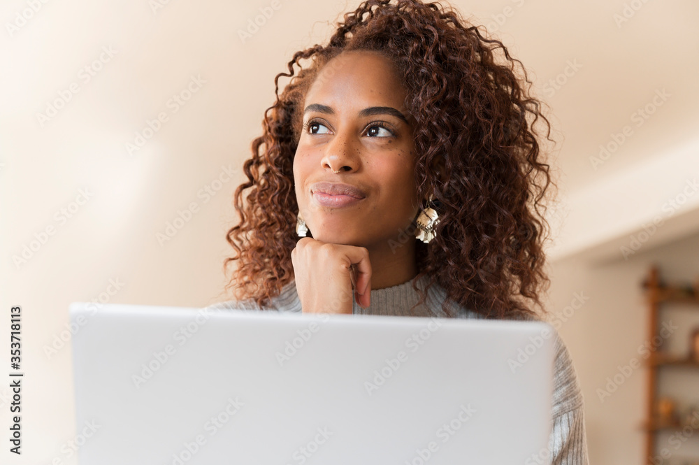 Woman thinking behind laptop Stock Photo | Adobe Stock