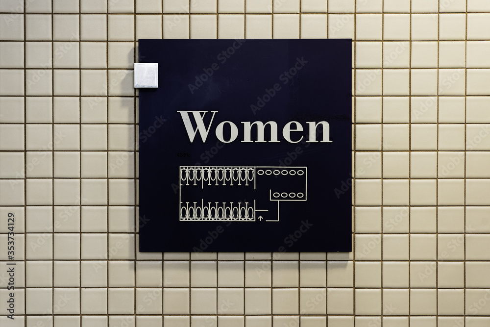 womens room sign on a tiled wall with a diagram of the stalls and sinks ...