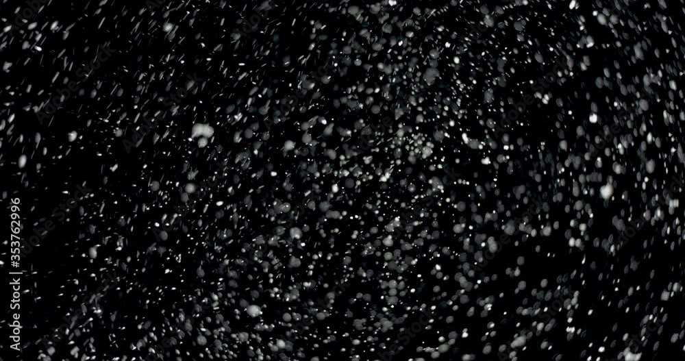 Snow rain falling from the sky at night. As the white particles fall ...