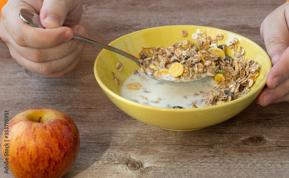 Fresh granola, muesli for breakfast. man eats cereal with milk from a ...