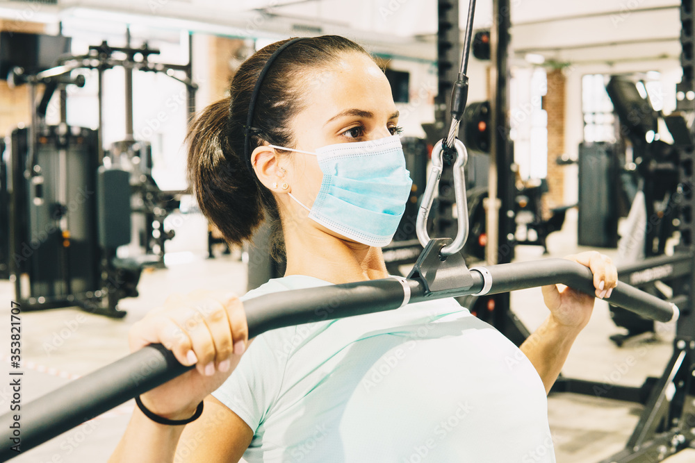 Young woman does strength exercises in a gym with her mask on. Stock ...