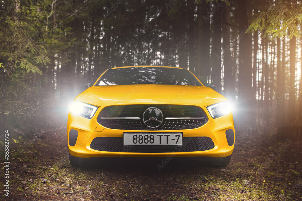 Frontal front view of a yellow car with dipped headlights on ...