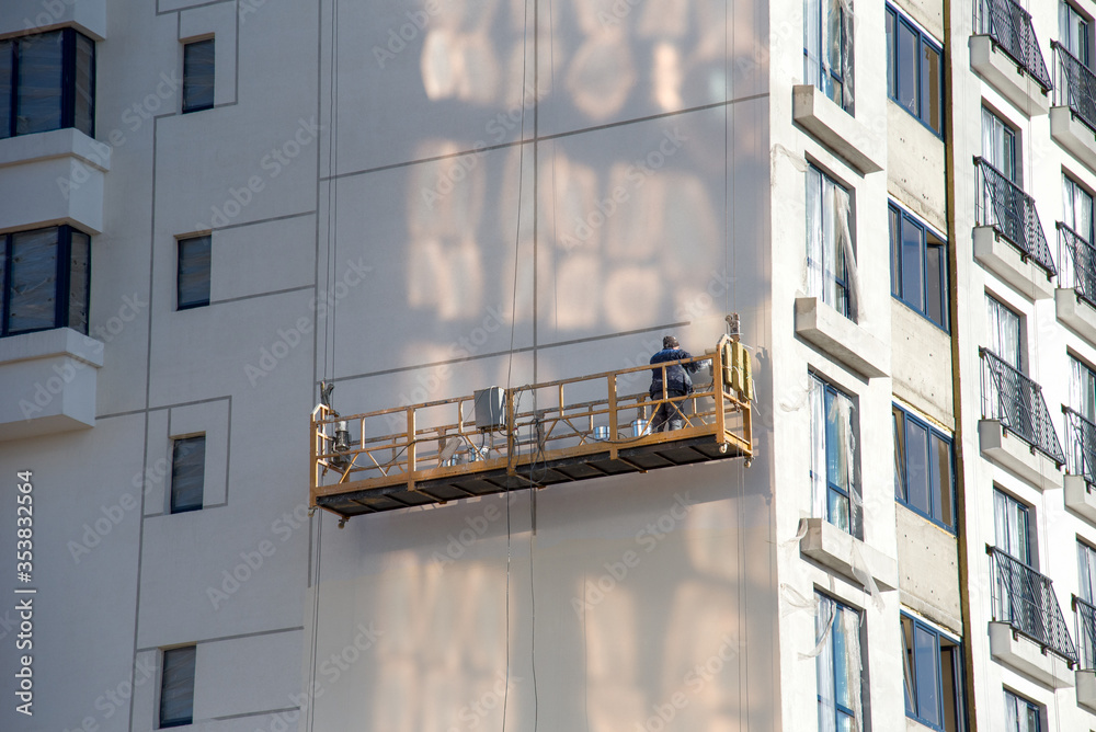 Builder on suspended construction cradle paint the shasad of a new ...