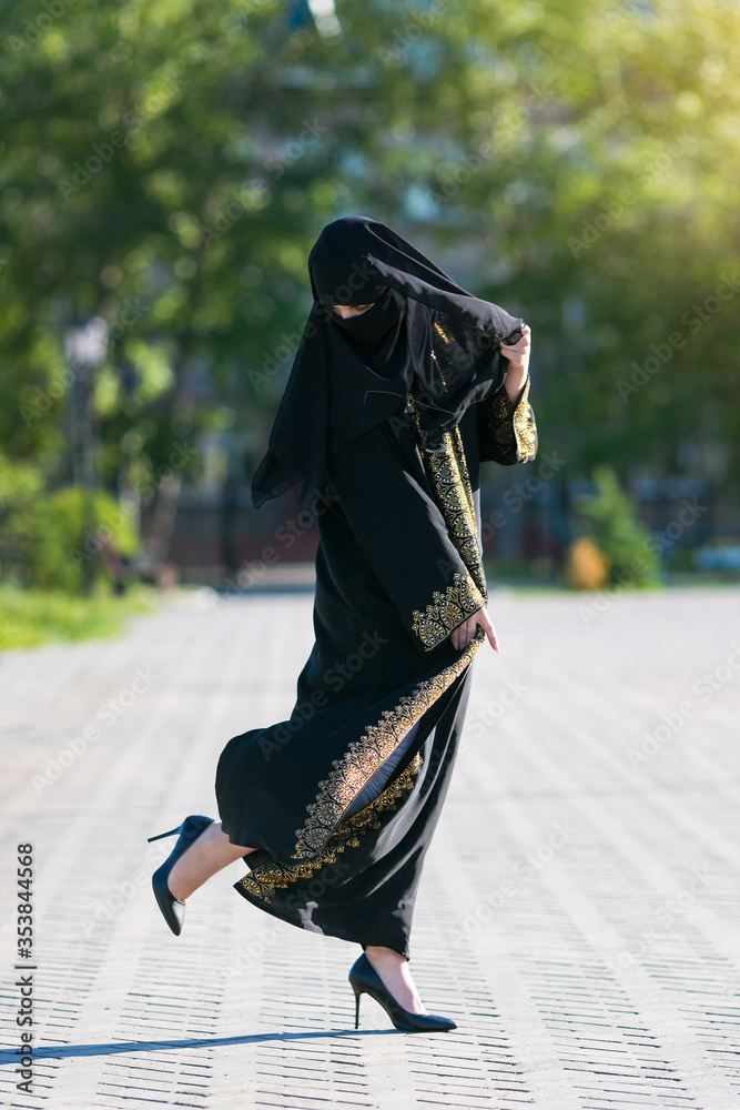 An Islamic woman in national dress wore high-heeled shoes. An Islamic ...