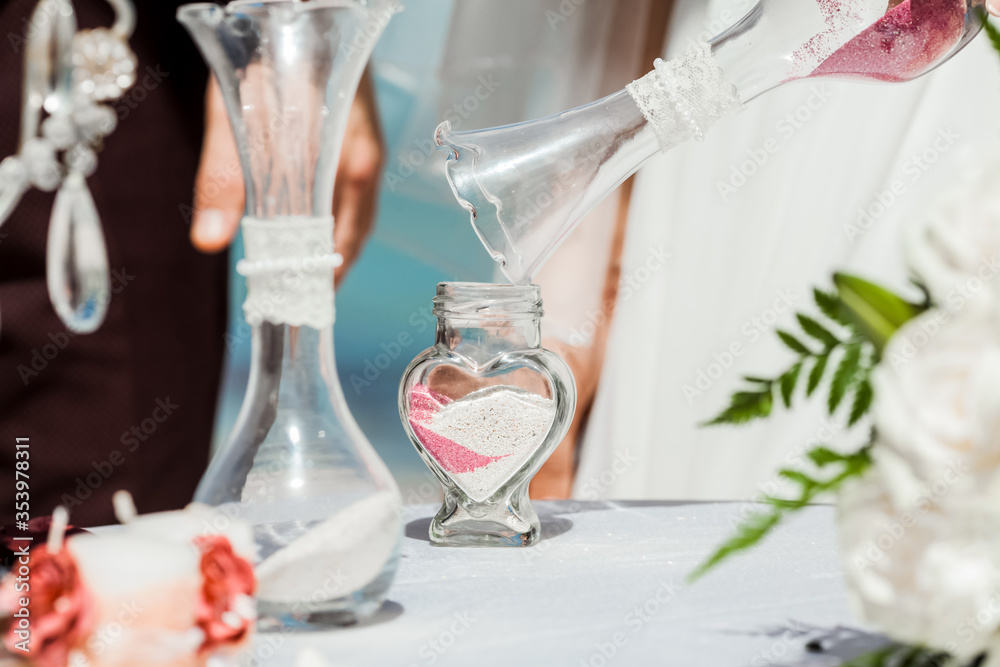 Bride and groom pouring colorful different colored sands into the ...