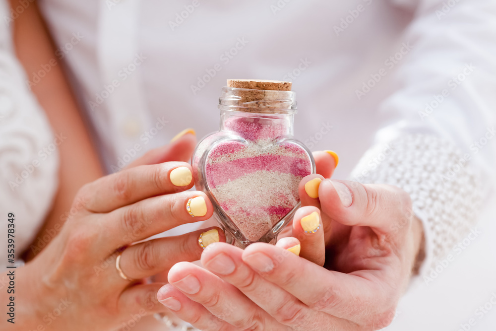 Bride and groom pouring colorful different colored sands into the ...