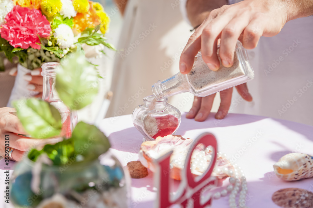Bride and groom pouring colorful different colored sands into the ...