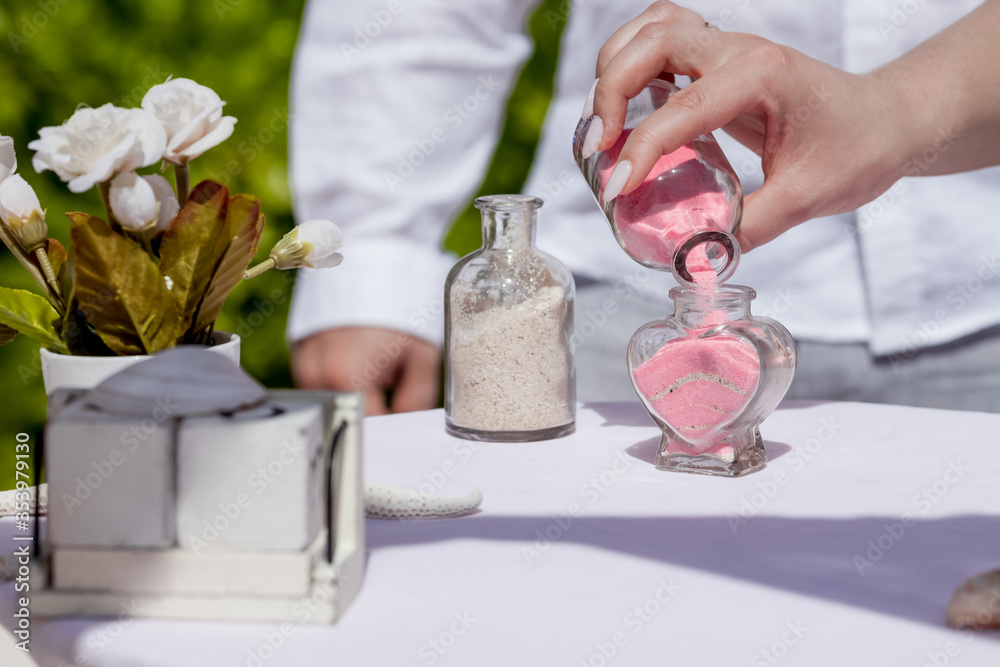 Bride and groom pouring colorful different colored sands into the ...