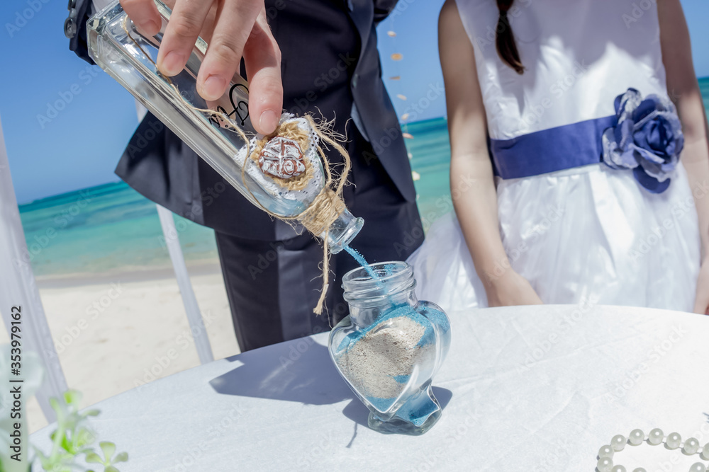 Bride and groom pouring colorful different colored sands into the ...