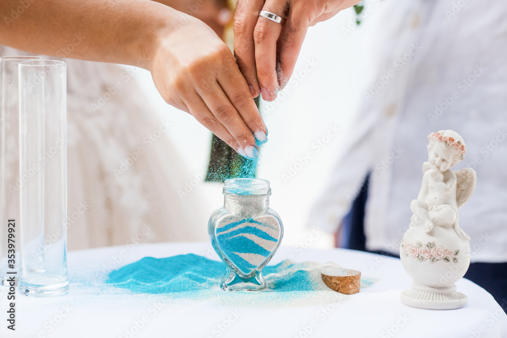 Bride and groom pouring colorful different colored sands into the ...