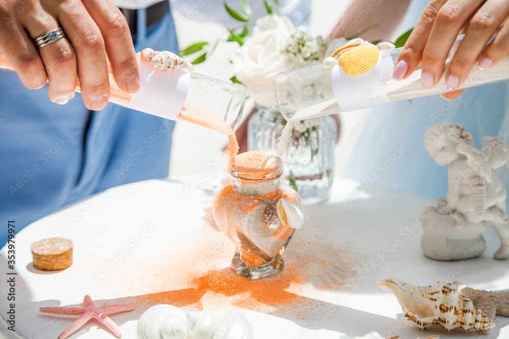 Bride and groom pouring colorful different colored sands into the ...