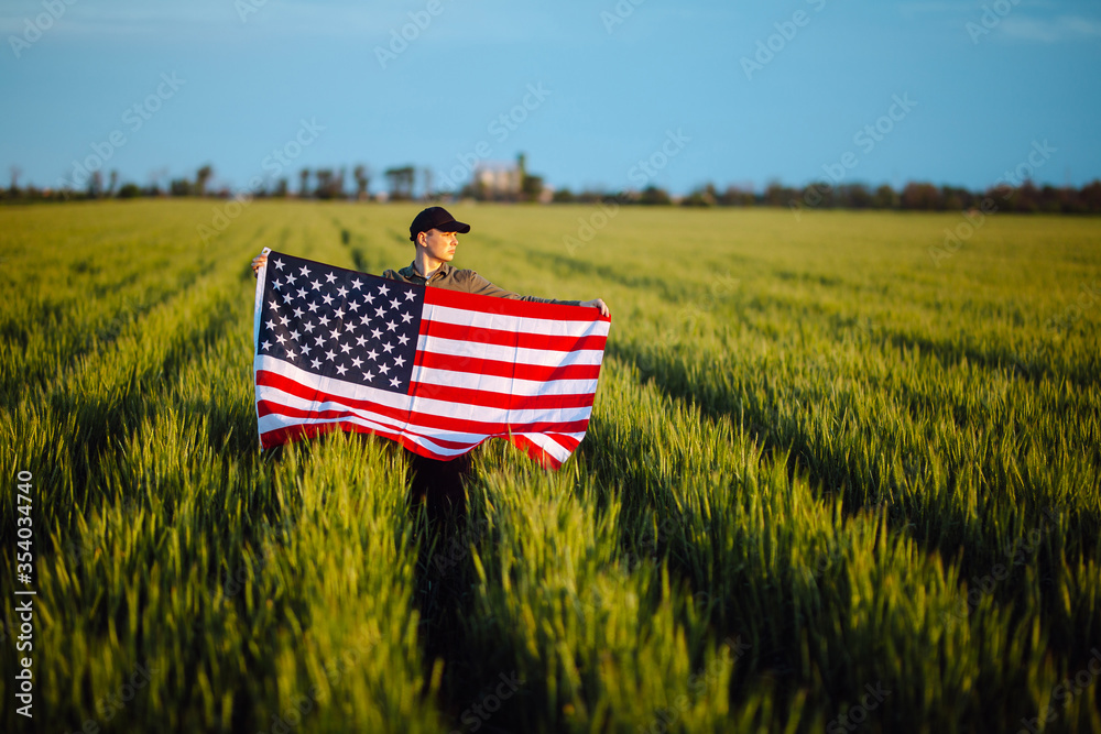 Young man wearing green shirt and cap lets the american flag fly on the ...