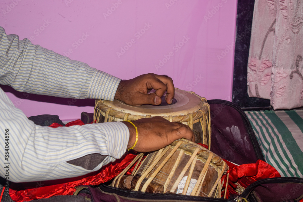 Musician adjusting his tabla with small hammer. Tabla is a traditional ...
